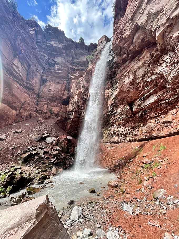 Cornet Creek plunges straight down through towering red canyon walls, landing with a splash that echoes off every surface around you.