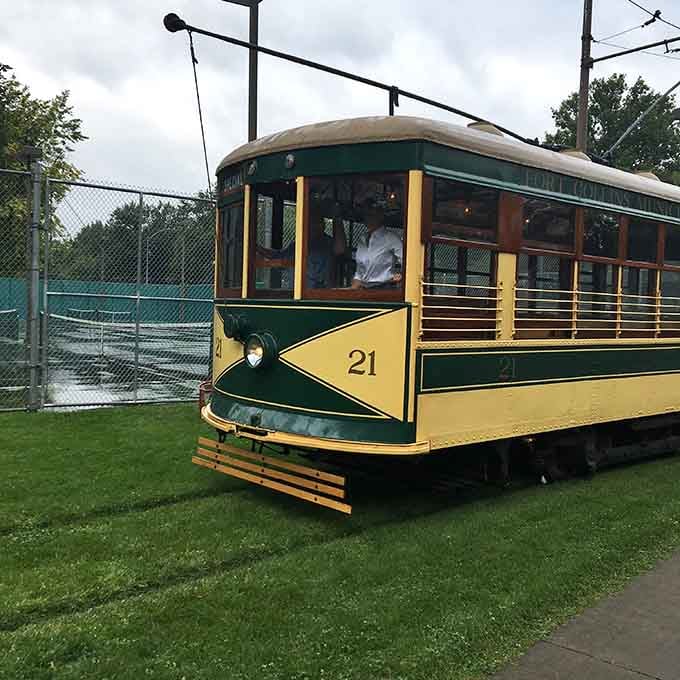 Fort Collins trolley car 21 sits quietly on the green grass, looking like a postcard from a gentler era.
