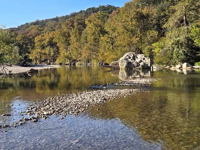 Crystal-clear Guadalupe River water mirrors autumn gold and limestone boulders in a scene almost too pretty to believe.