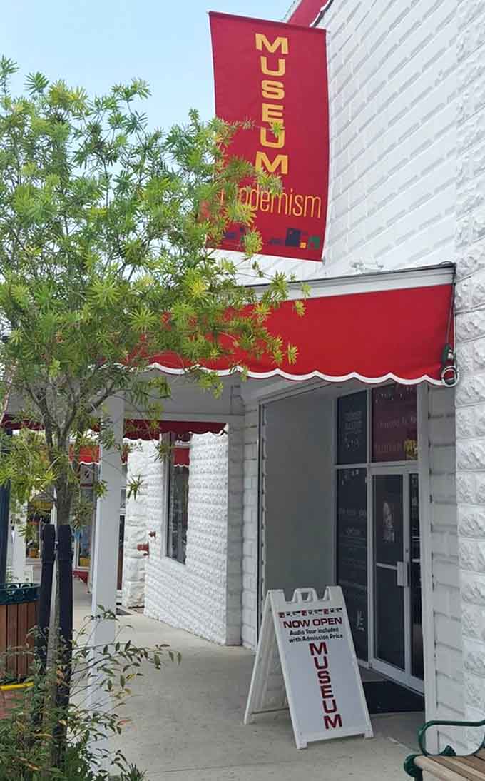 That bold red awning and "Museum of Modernism" banner practically shout from the sidewalk, promising something wonderfully unexpected just beyond the front door.