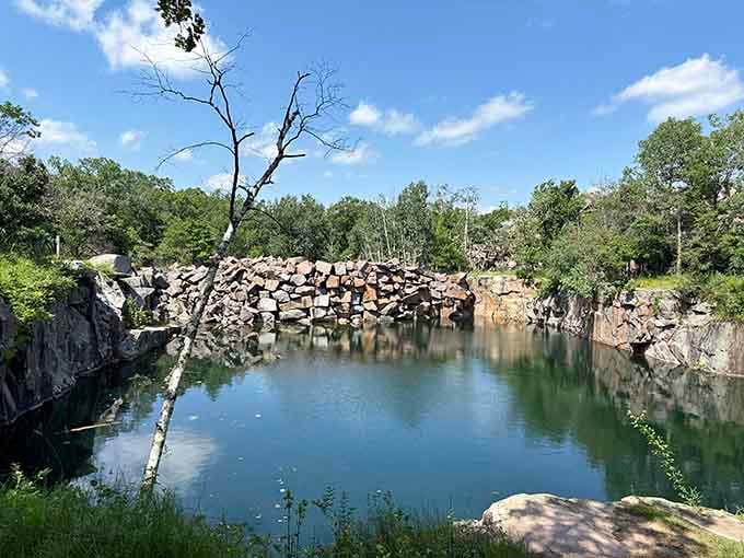 Still water mirrors a wall of stacked granite, turning this old quarry into something almost impossibly beautiful.
