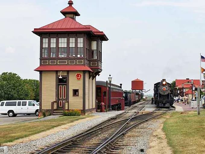 That vintage railroad tower stands proud beside gleaming locomotives, celebrating an era when travel meant adventure.