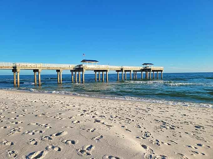 The fishing pier extends into crystal-clear water, inviting anglers to try their luck in this postcard-perfect Gulf setting.