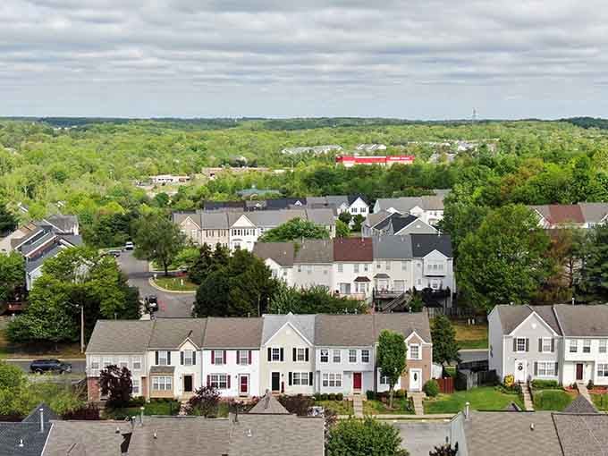 Get a wonderful bird's-eye view of neat rows of lovely suburban townhomes surrounded by dense, vibrant green summer forests.