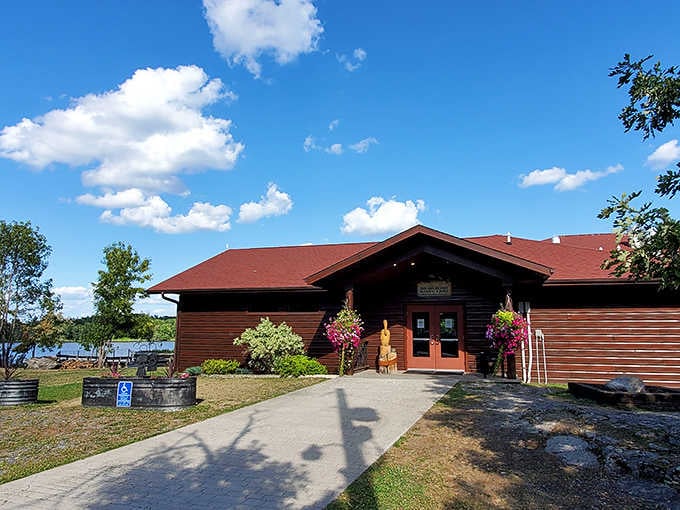 Bright hanging flowers and a carved wooden figure greet visitors at Island View's charming lakeside welcome center entrance.