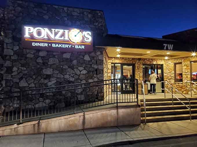 Evening lights illuminate the welcoming entrance where the promise of fresh-baked goods and hearty meals awaits inside patiently.