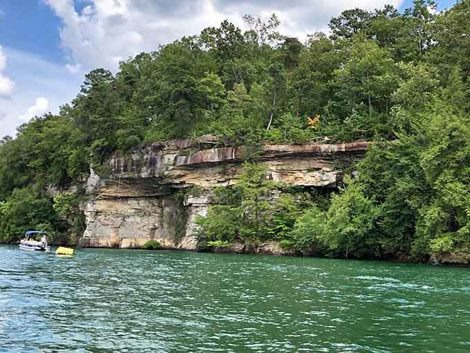 Layered sandstone cliffs rise straight from that impossibly green water, making every boat ride feel like an adventure.