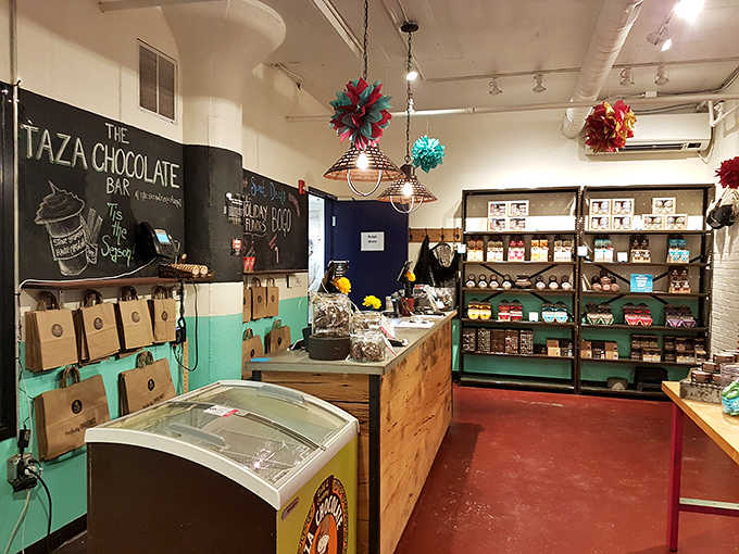 Colorful ornaments dangle above shelves packed with stone-ground chocolate that proves candy can be both art and delicious rebellion.