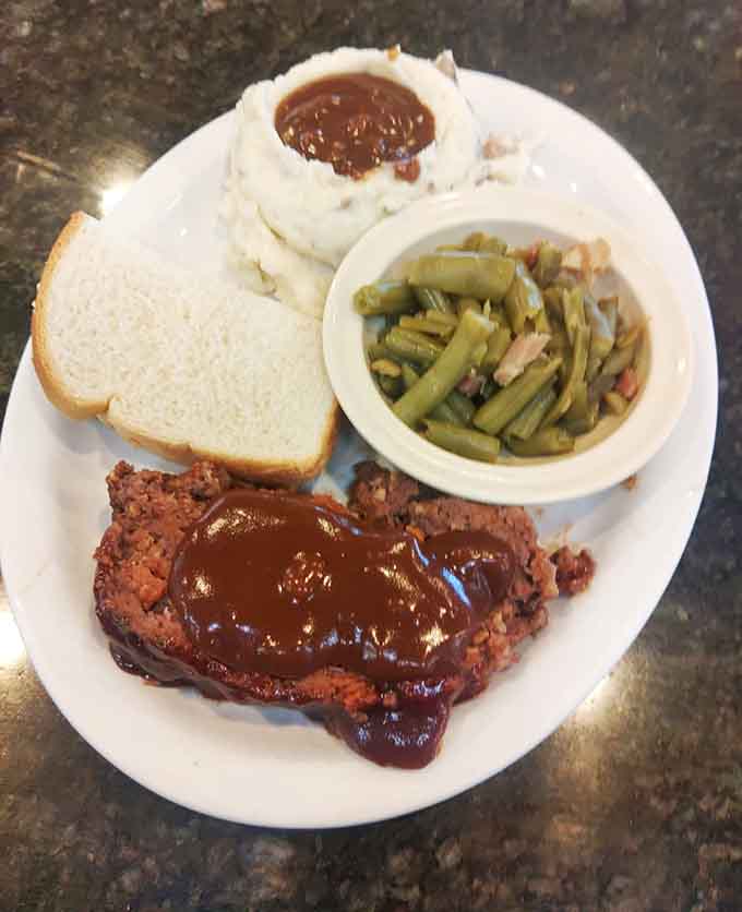 Meatloaf smothered in rich sauce, flanked by mashed potatoes and green beans. Pure, unapologetic comfort on a plate.