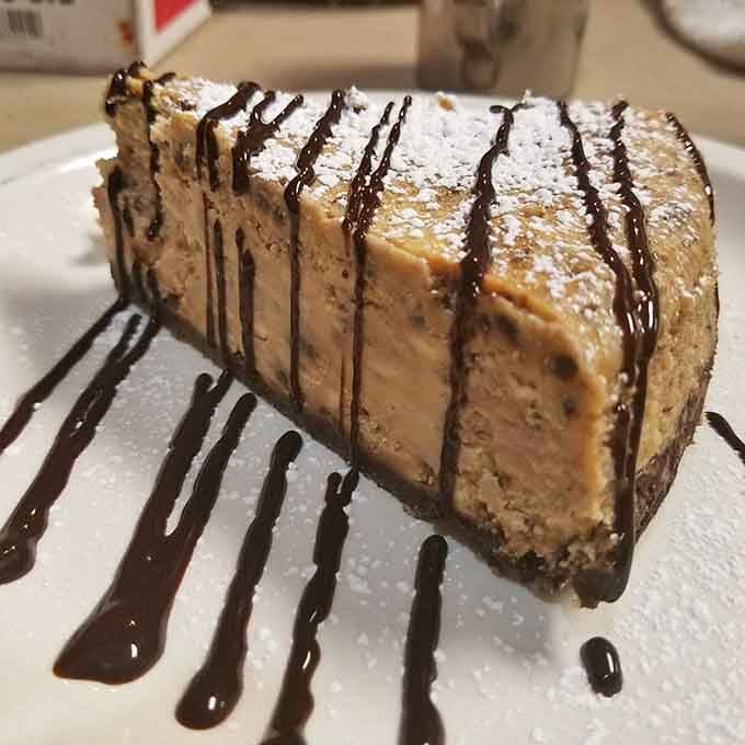 Dusted with powdered sugar and drizzled with chocolate, this cheesecake slice deserves its own standing ovation and encore.