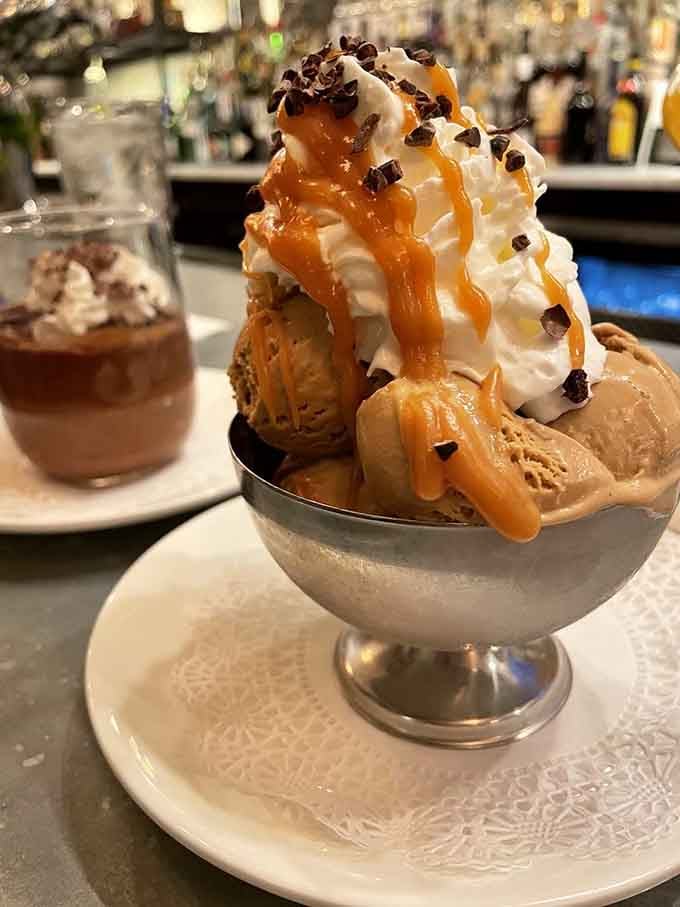 This ice cream sundae towers like something from a 1950s soda fountain, dripping with caramel and pure joy.