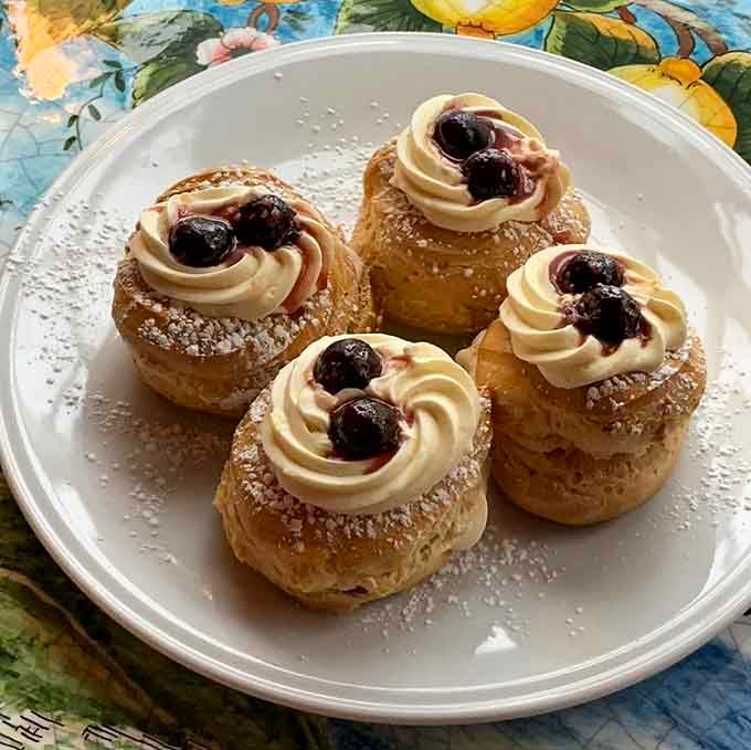 Pillowy cream-topped pastries dusted with powdered sugar and finished with cherries, dessert here is not an afterthought.