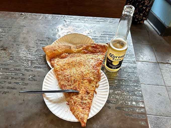 When your pizza slice needs its own zip code and a Corona for moral support.