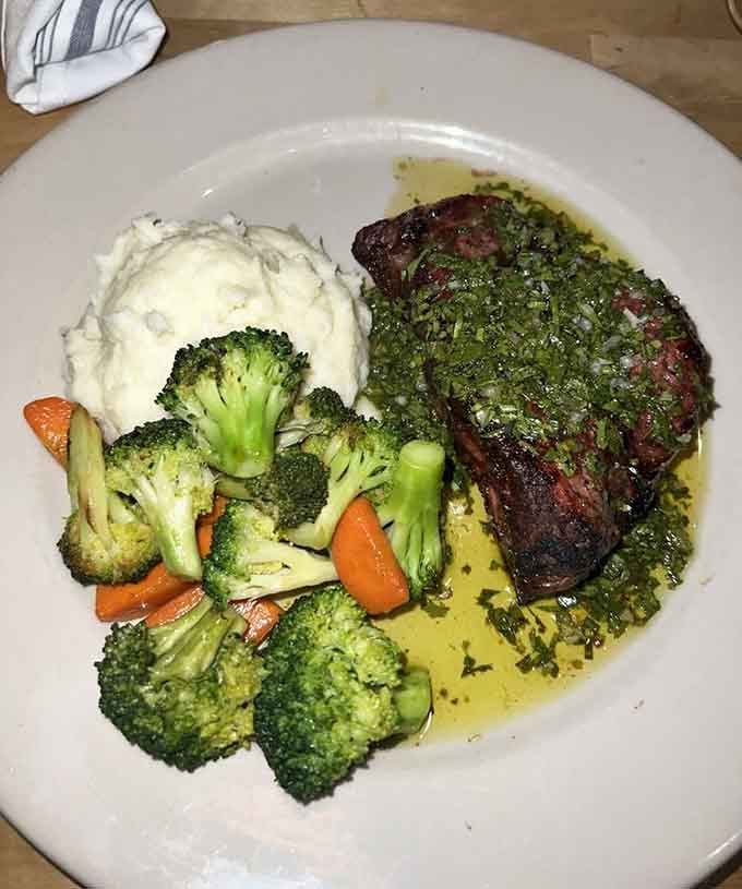 Angus steak topped with chimichurri and sided with vegetables, because balance matters even at steakhouses.