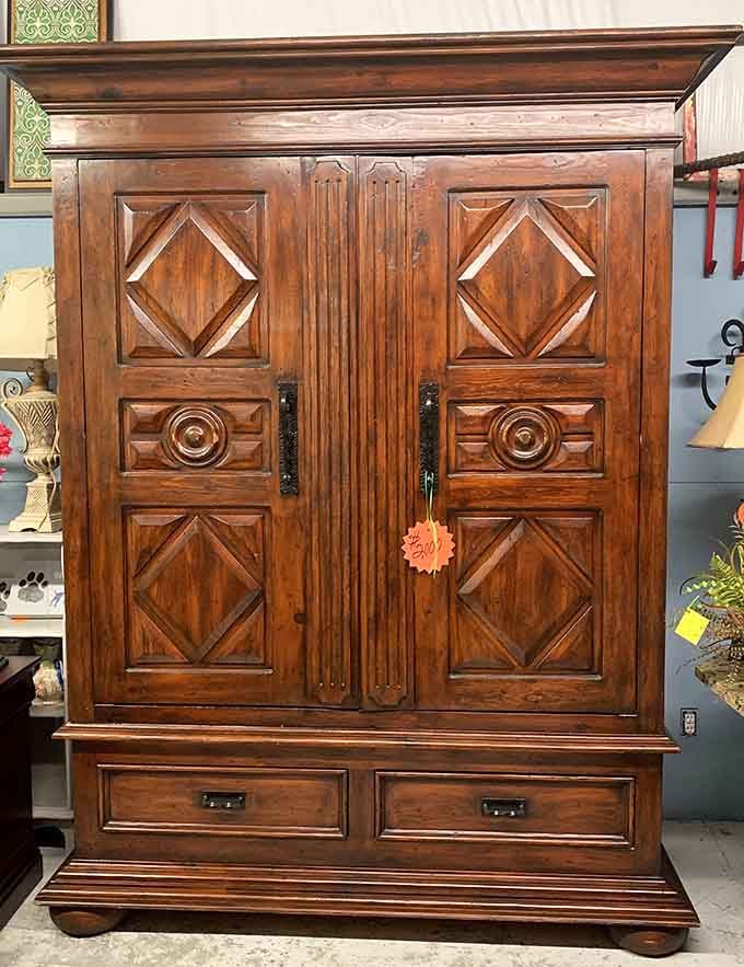 A massive carved wood armoire with diamond panel doors and bun feet, the kind of furniture that makes a room stop and pay attention.