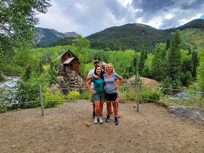 Visitors pose with their prize, having earned this view through miles of hiking or white-knuckle driving.