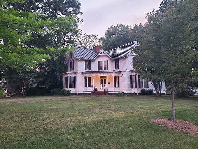 A glowing porch, Victorian gingerbread trim, and a sweeping lawn at dusk make this Davidson home look straight out of a Southern novel.