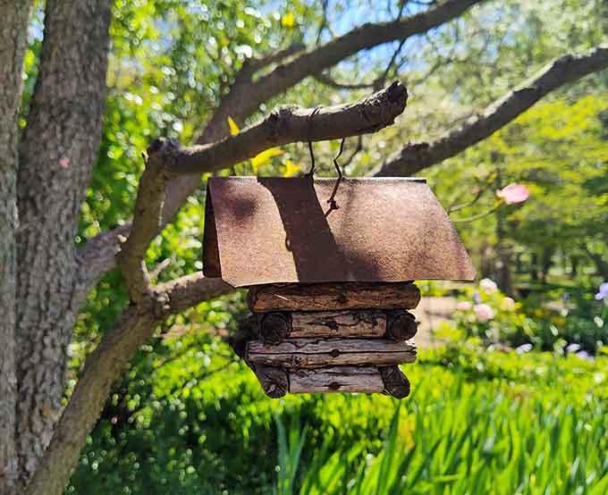 A handmade birdhouse hanging in a flowering tree. Even the birds here have good taste.