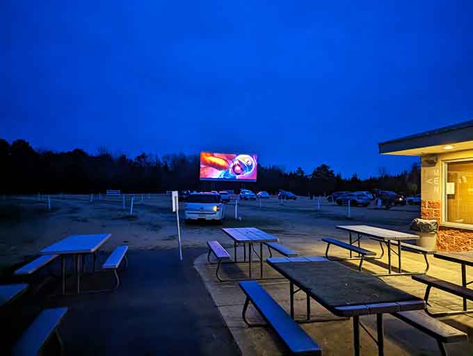 Picnic tables, a lit-up concession building, and a movie playing in the distance. The whole scene just works.
