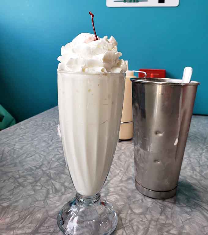 Whipped cream, a cherry on top, and a steel mixing cup on the side &mdash; a milkshake done with full commitment.