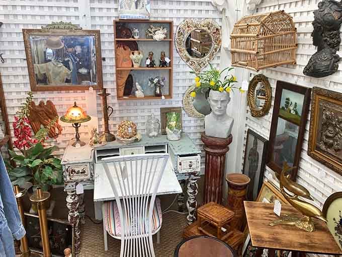 A booth so beautifully layered with mirrors, busts, and framed art it feels like stepping into a Parisian flea market.