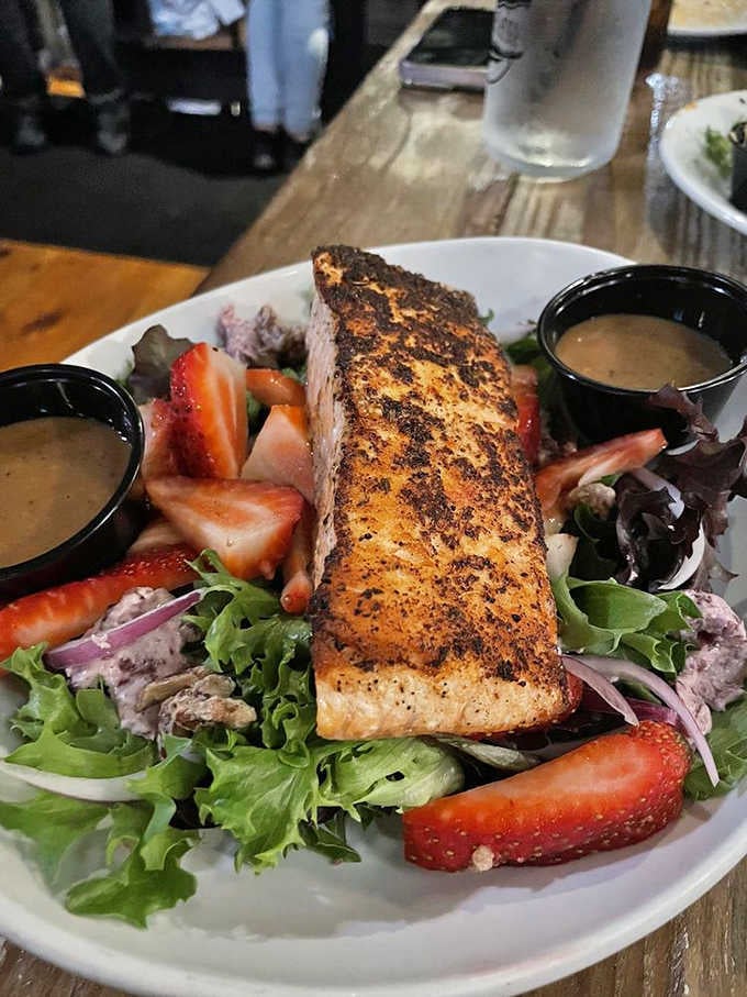 Blackened salmon perches atop fresh greens with strawberries, proving healthy eating doesn't have to mean boring eating.