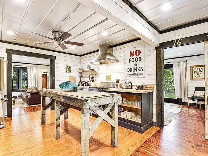 A rustic worktable island, a bold "No Food Or Drinks Beyond This Point" sign, and a kitchen that dares you to cook something great.