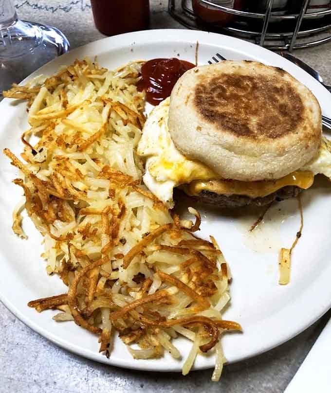 A breakfast sandwich on an English muffin with hash browns crispy enough to hear across the diner.