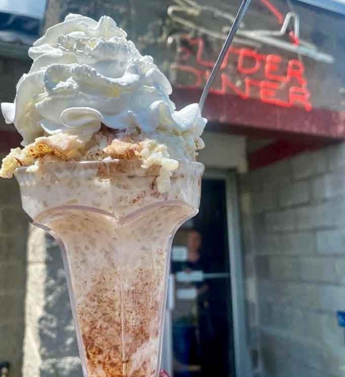 Towering whipped cream, crumbled toppings, and the Glider Diner sign glowing behind it, this milkshake has serious main character energy.