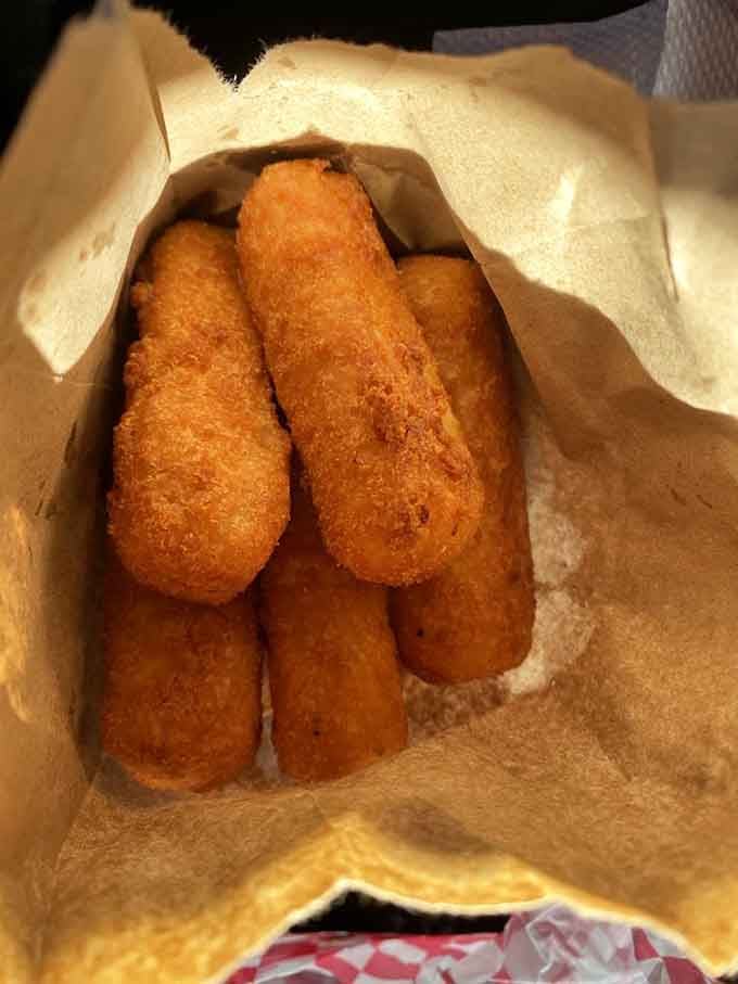 Golden, crispy cheese sticks tucked into a paper bag like a delicious little surprise waiting to happen.