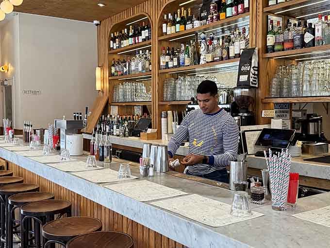 A focused bartender, a marble counter, and shelves stacked with serious bottles. This bar means genuine, thoughtful business.