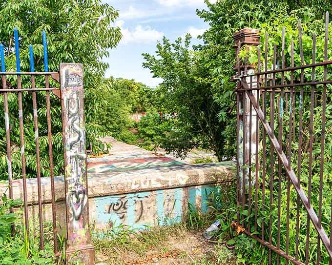 The rusted gates stand open, inviting explorers into a world where urban decay becomes unexpected beauty.