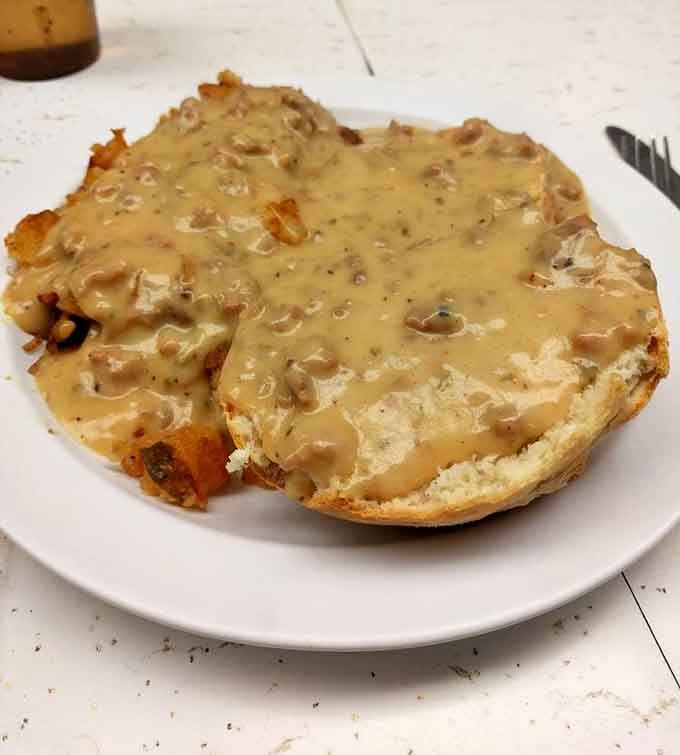 Sausage gravy poured generously over an English muffin, rich, savory, and completely unapologetic about it.