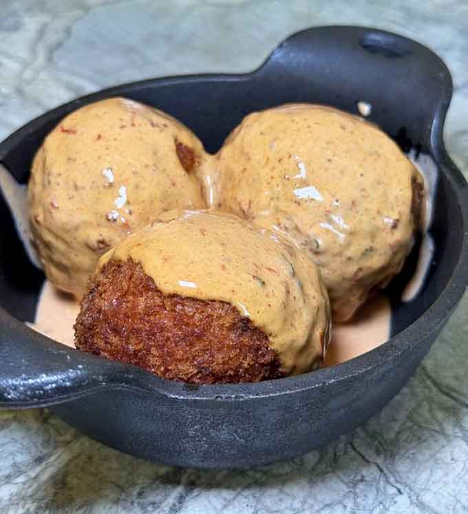 Golden-fried mac and cheese balls deliver crispy exteriors and molten cheese centers that defy all dietary logic.