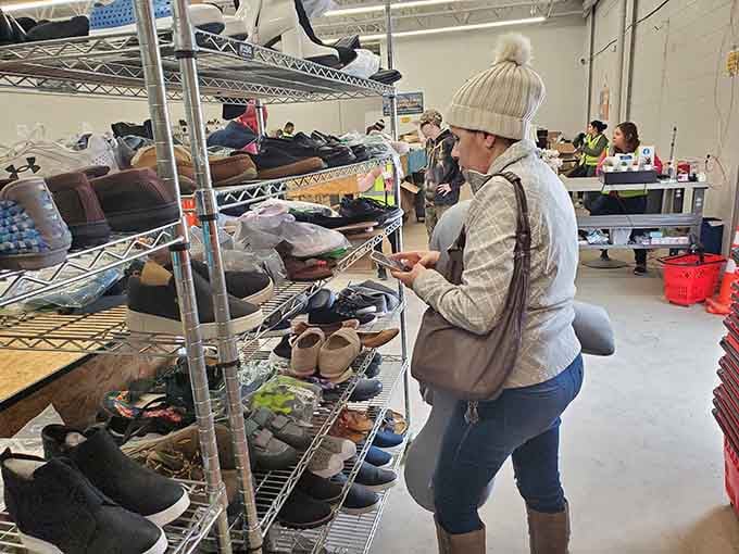 A focused shopper carefully evaluating the shoe rack, phone in hand, treating every find like a serious business decision.