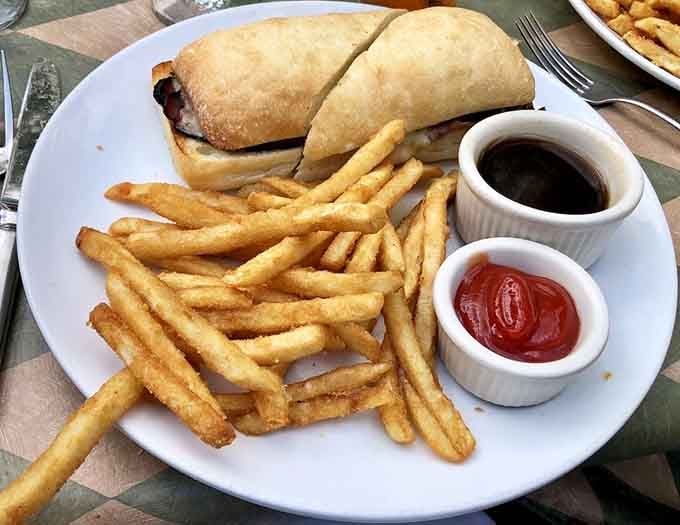 A hearty sandwich with golden fries, au jus, and ketchup on the side, comfort food dressed up for a nice occasion.
