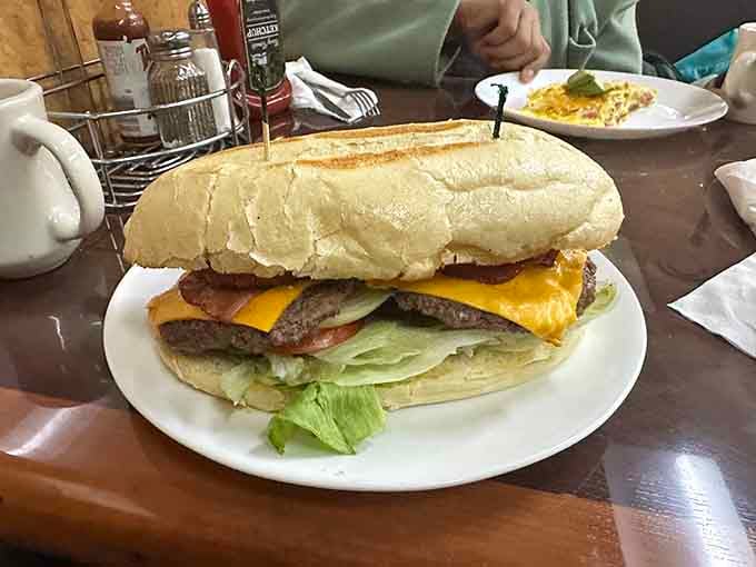 That towering cheeseburger on a crusty roll, stacked with bacon, lettuce, and tomato, is not here to play games.