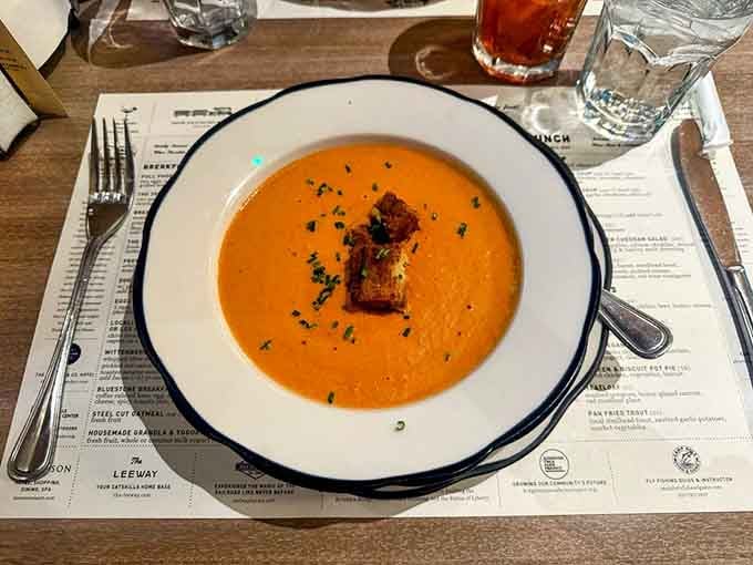 Creamy tomato soup with croutons floating on top tastes like childhood memories in a bowl.