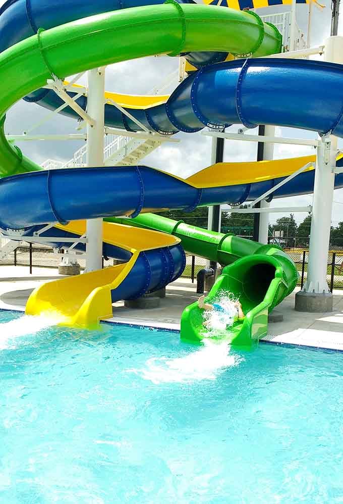 Green, blue, and yellow slides launching riders into sparkling water. Pure, unfiltered joy, delivered at speed.