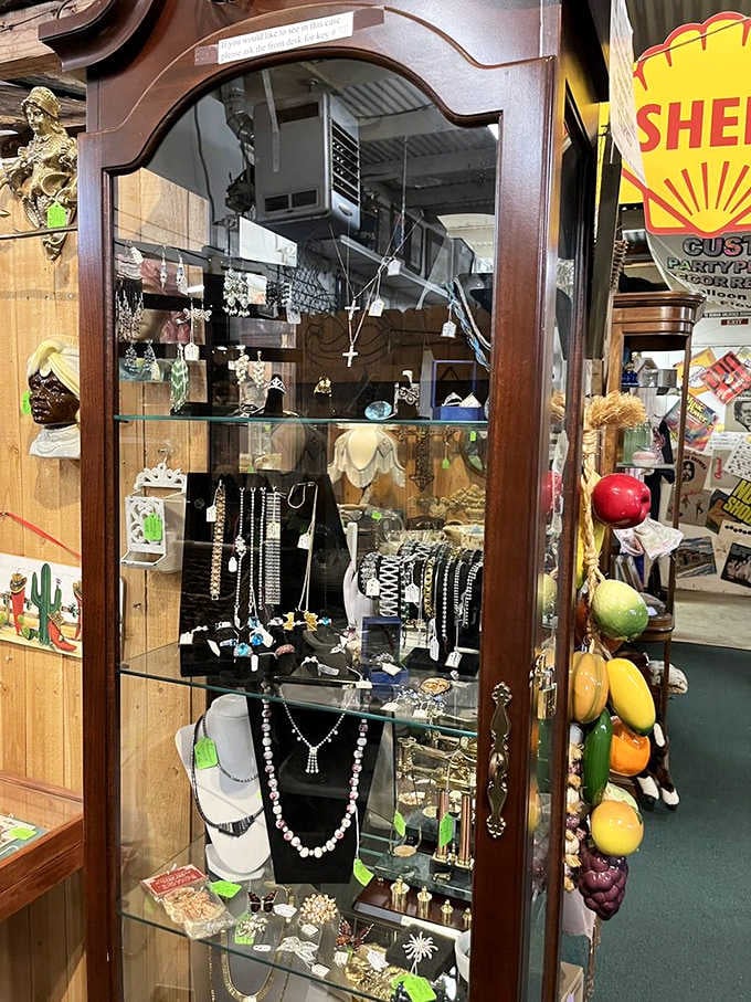 A mahogany display cabinet filled with necklaces, earrings, and bracelets, each piece quietly waiting for someone to take it home.