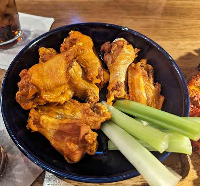 Saucy, golden wings served with celery in a dark bowl. Simple, honest, and absolutely impossible to stop eating.