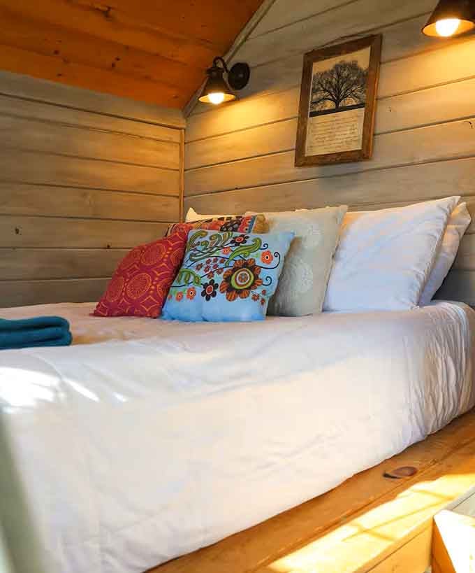 Clean white linens, colorful pillows, and soft lighting. Sleep has never looked this good up in the trees.