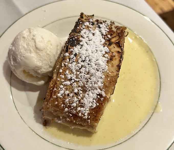 Warm apple strudel dusted with powdered sugar, sitting next to a scoop of vanilla ice cream. Pure joy.