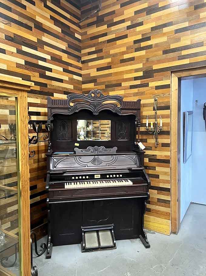 A beautifully ornate vintage pump organ tucked against a reclaimed wood wall, waiting patiently for someone to sit down and play.