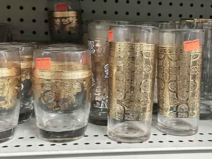 Gold-etched glassware sitting quietly on a shelf, looking like it belongs at a fancy dinner party, not a bargain store aisle.
