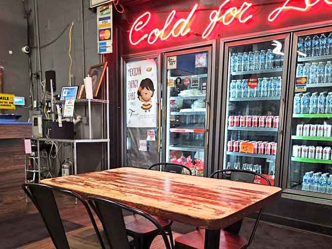 A glowing neon sign, cold drinks stacked high, and a wooden table waiting just for you.