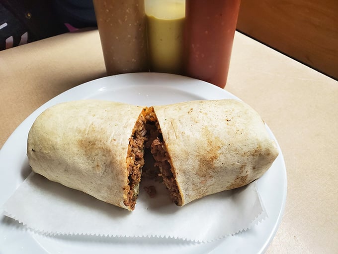 A burrito cut clean in half, revealing a packed interior of rice, beans, and seasoned meat.