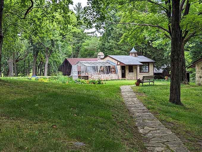 A stone path leads to a charming greenhouse cottage, proof that even outbuildings here have personality.