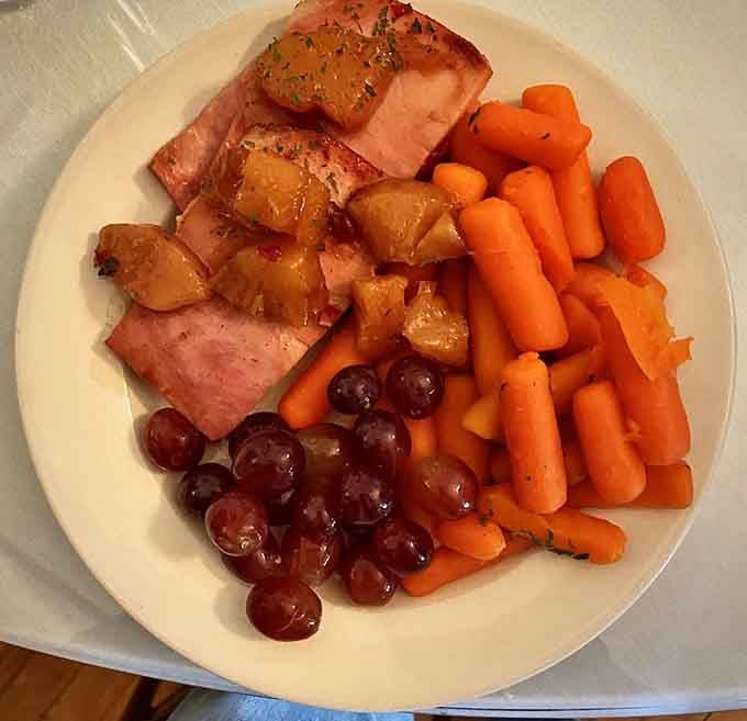 Glazed salmon, honey-kissed carrots, red grapes, and caramelized fruit, a plate that looks like a painting and tastes even better.