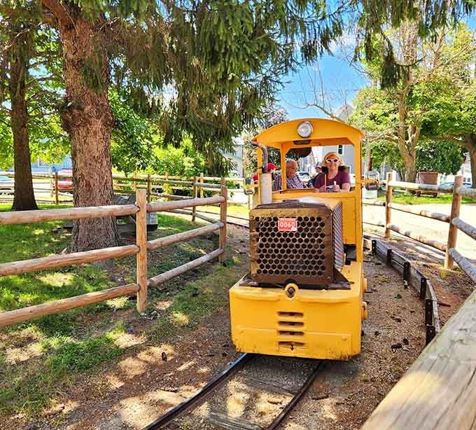 This cheerful yellow mine locomotive once hauled ore; now it hauls smiling visitors through sunny Platteville grounds.